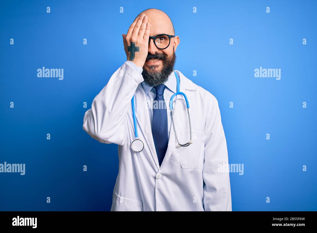 Handsome bald doctor man with beard wearing glasses and stethoscope ...