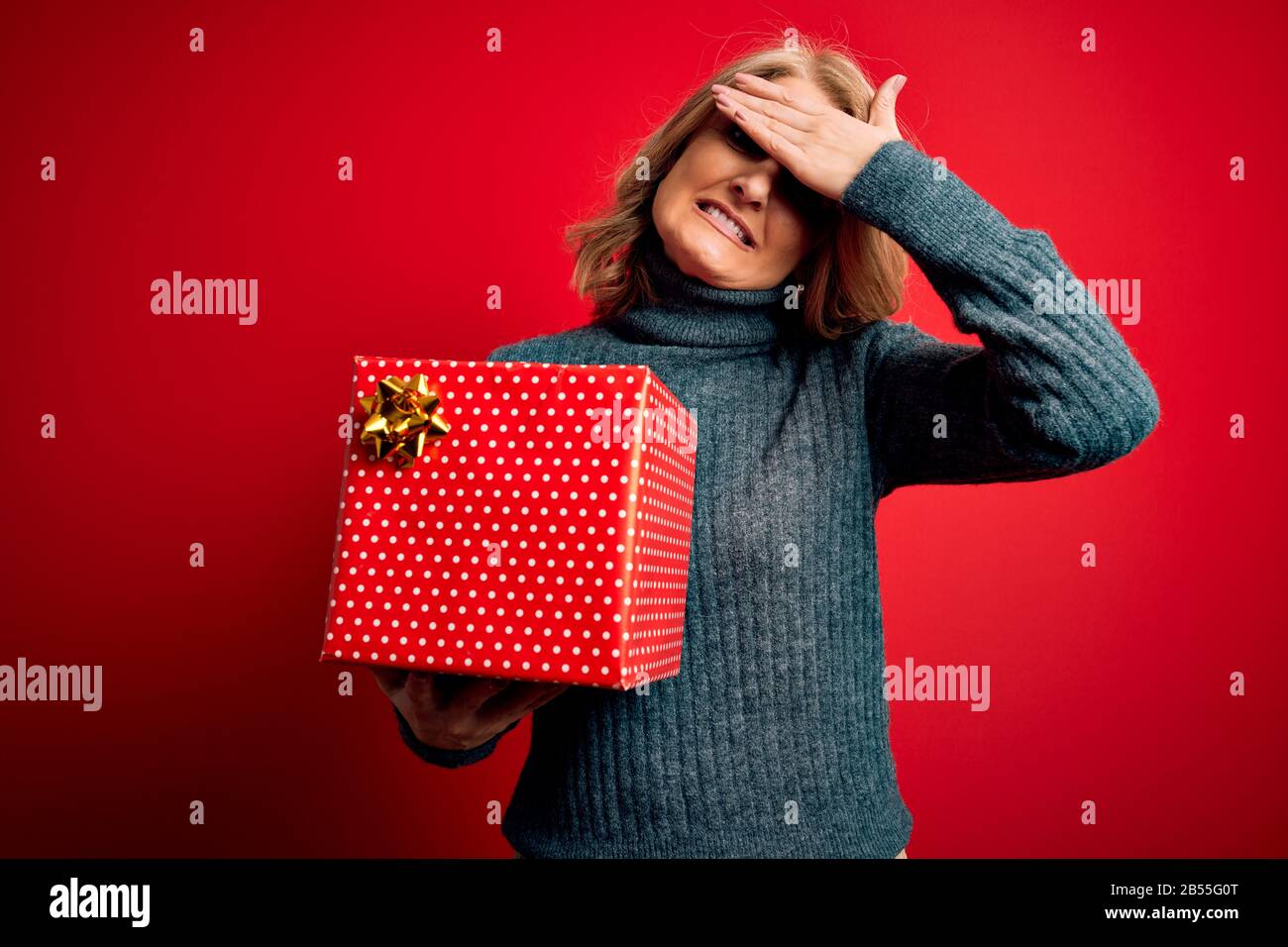 Middle age beautiful blonde woman holding birthday gift over isolated ...