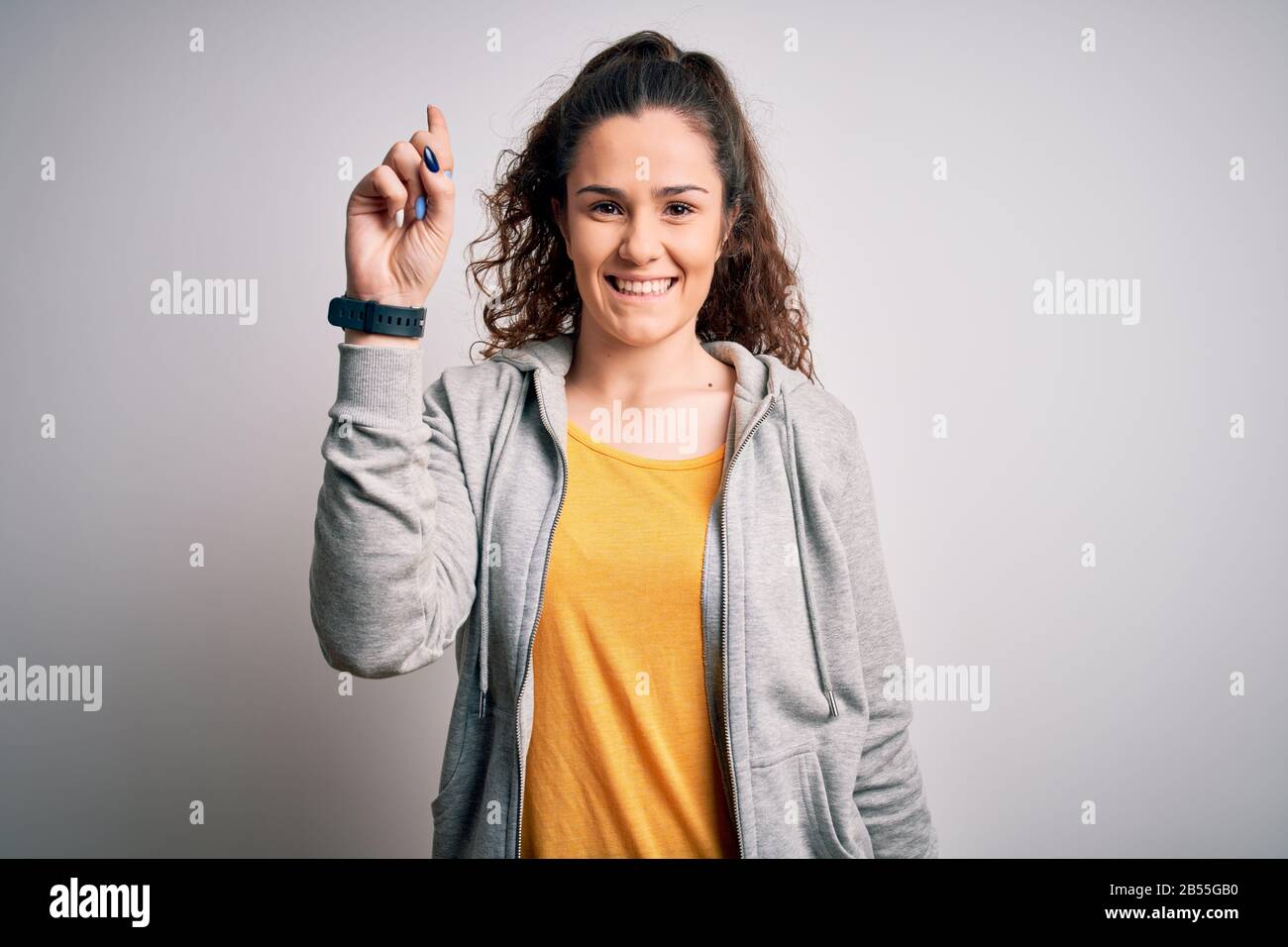 Young beautiful sportswoman with curly hair wearing sportswear over ...