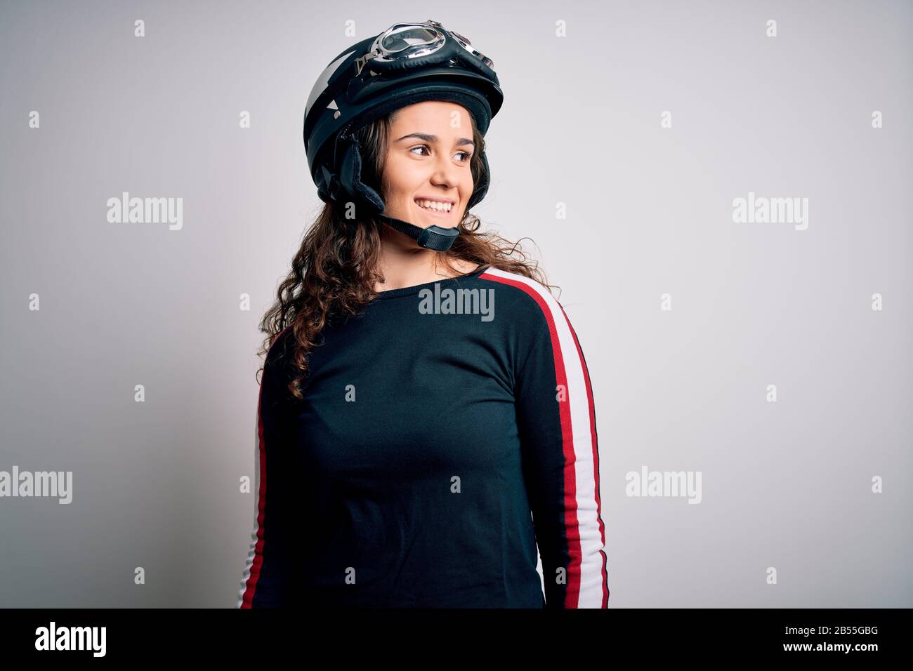 Beautiful motorcyclist woman with curly hair wearing moto helmet over ...