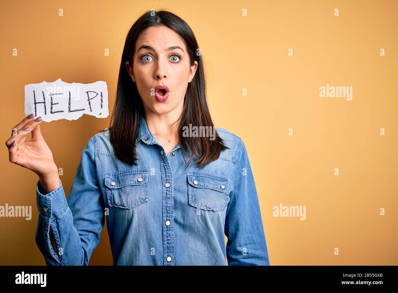 Young brunette woman with blue eyes holding for help and protection ...