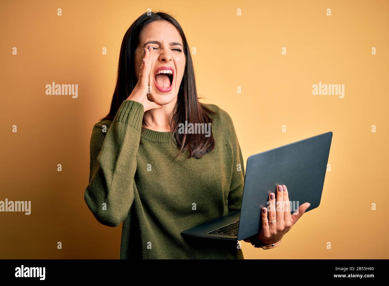 Young brunette woman with blue eyes working using computer laptop over ...