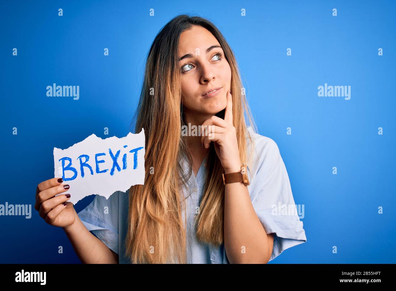 Young beautiful blonde woman with blue eyes holding banner with brexit ...