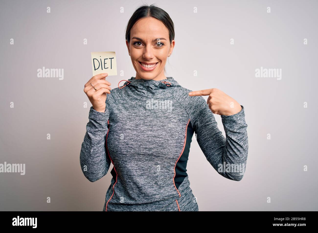 Young fitness woman wearing sport workout clothes holding paper with ...