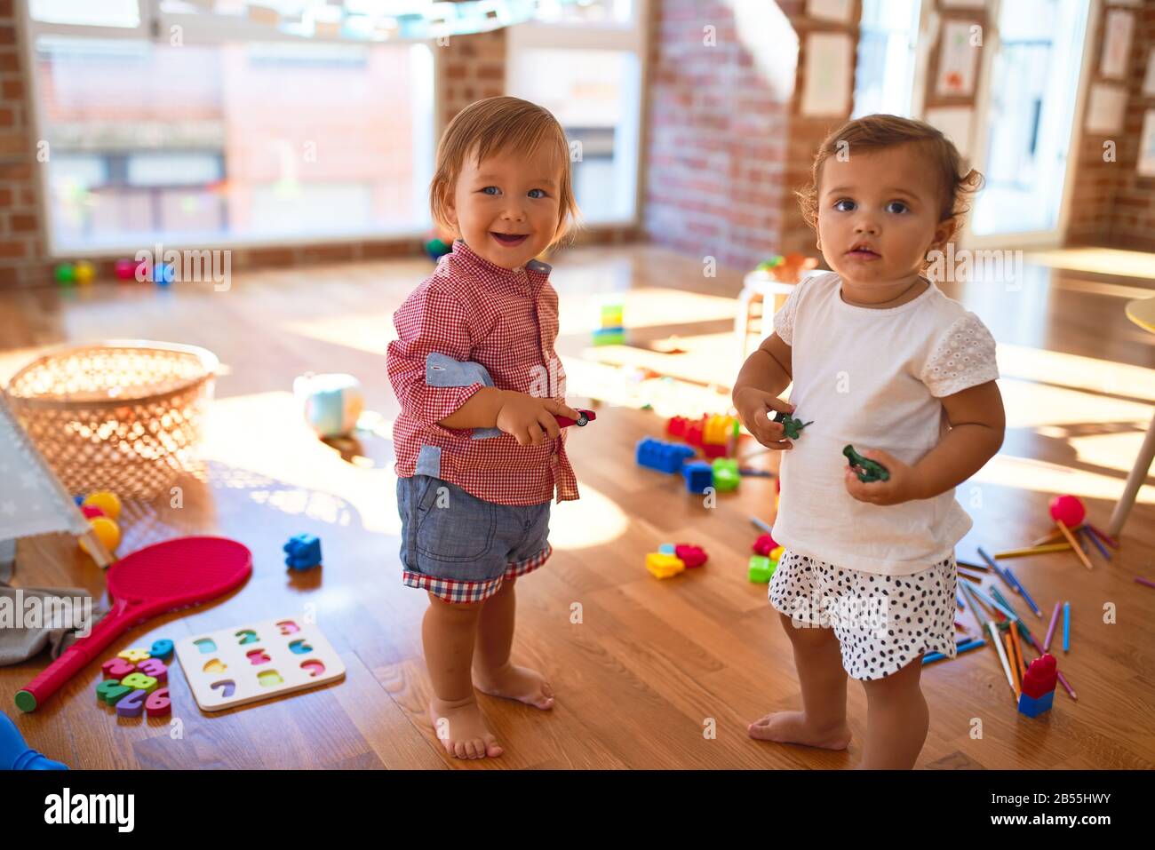 Adorable toddlers playing around lots of toys at kindergarten Stock ...