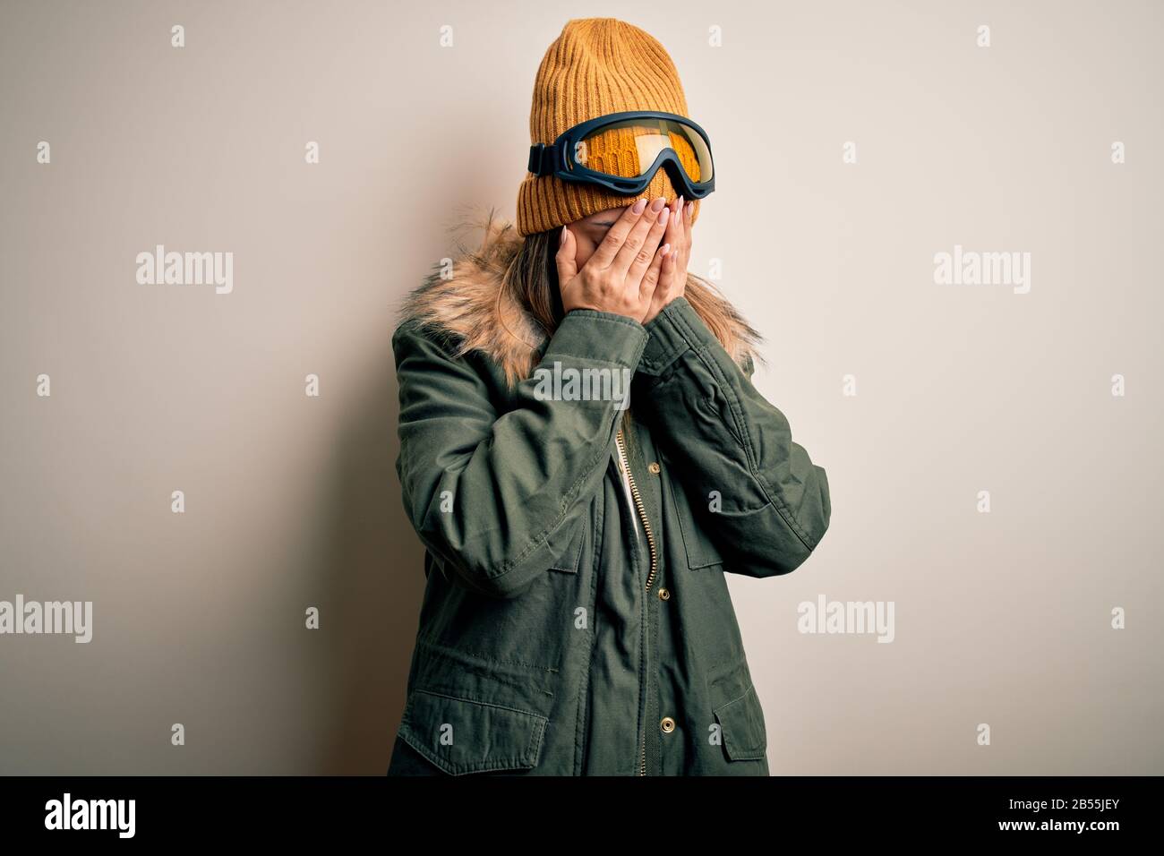 Young brunette skier woman wearing snow clothes and ski goggles over ...