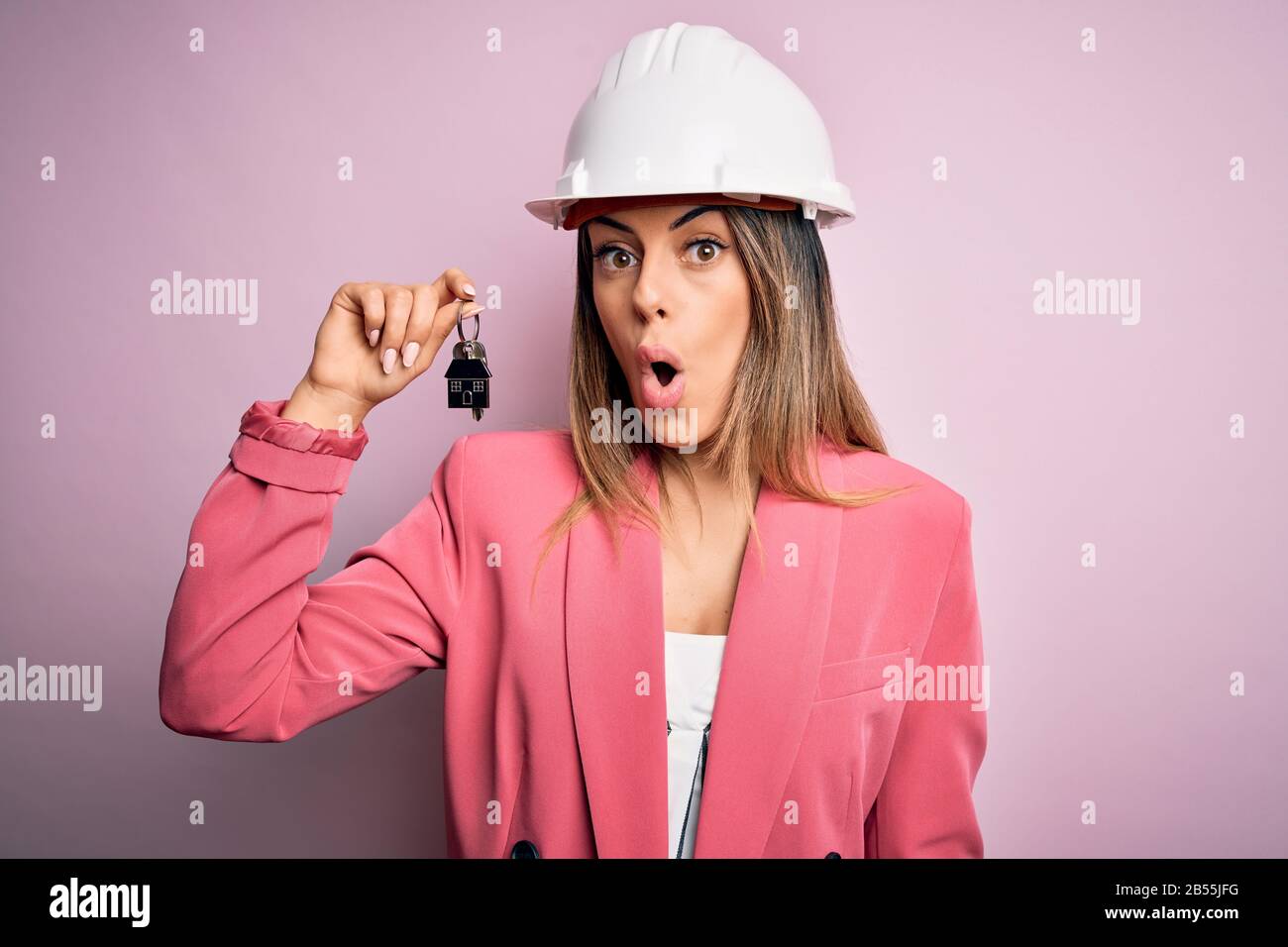 Young beautiful brunette architect woman wearing safety helmet hoding ...