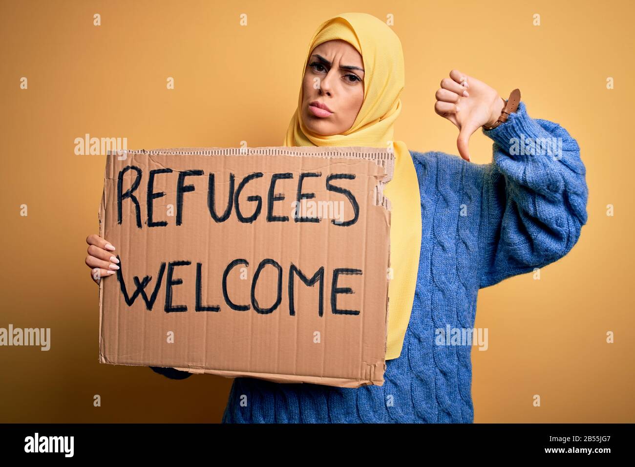 Beautiful arab woman wearing islamic hijab holding banner with refugees ...