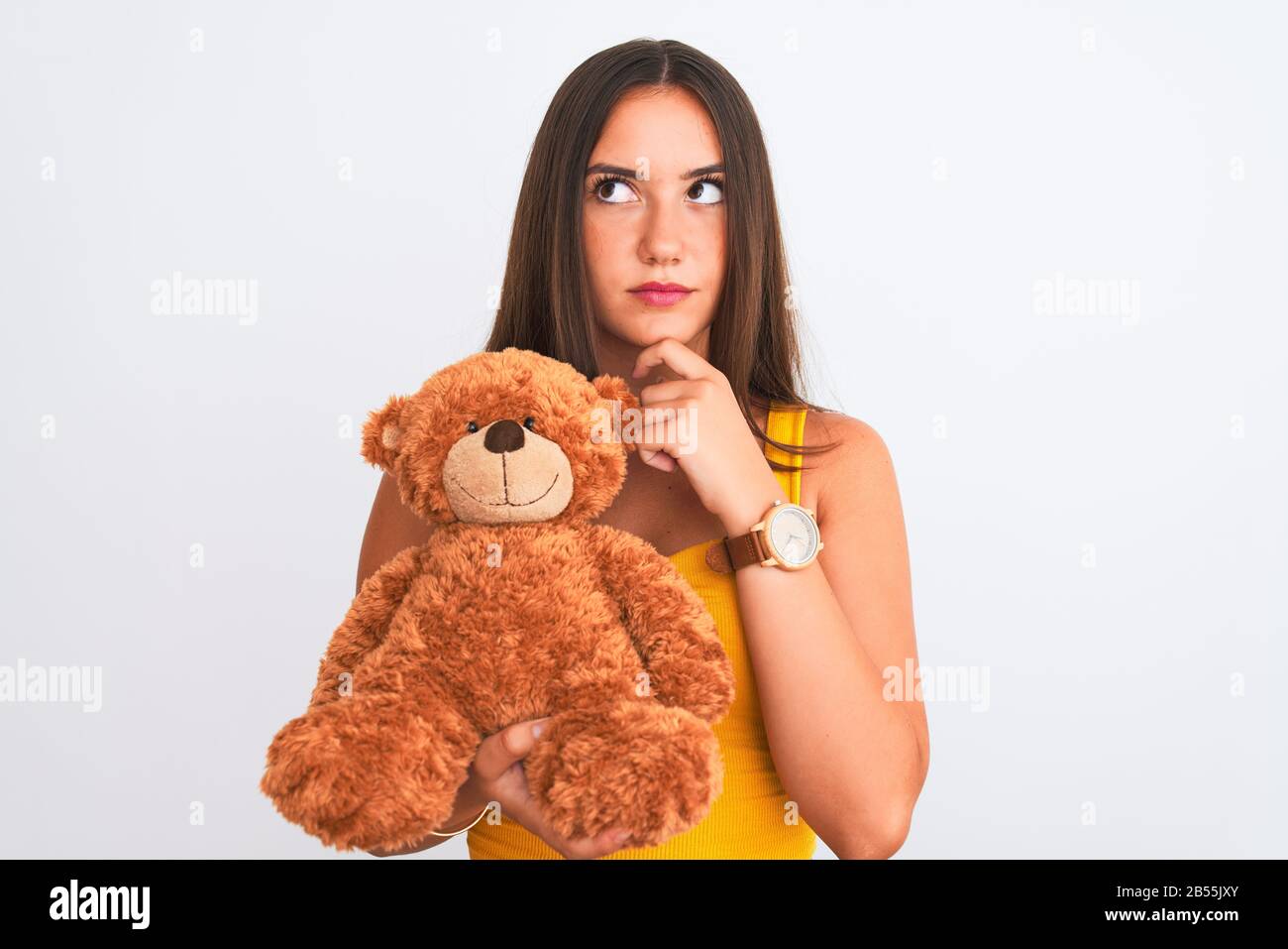 Young beautiful girl holding cute teddy bear standing over isolated ...