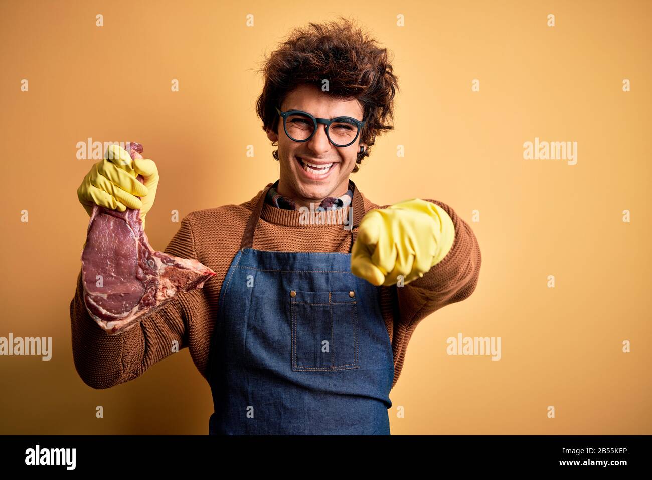 Young handsome butcher man holding meet steak standing over isolated ...