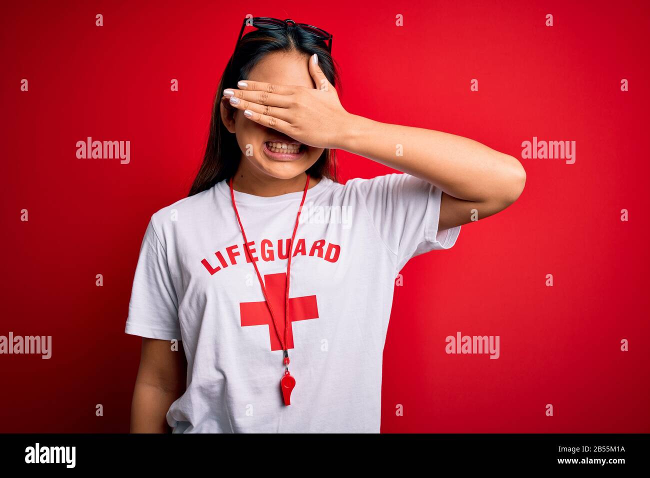 Young asian lifeguard girl wearing t-shirt with red cross using whistle ...