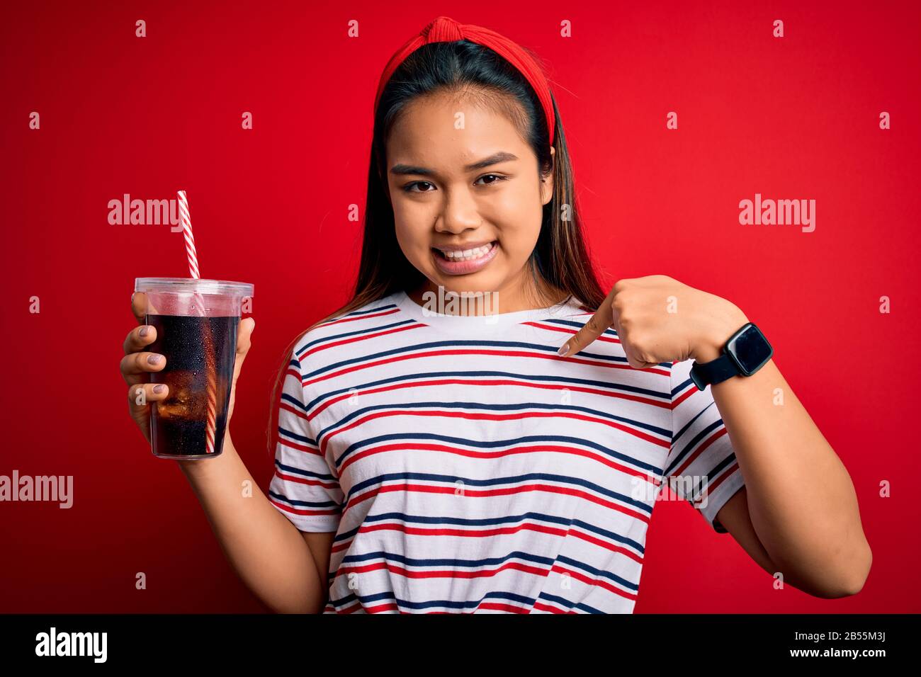 Young asian girl drinking cola fizzy refreshment using straw over ...