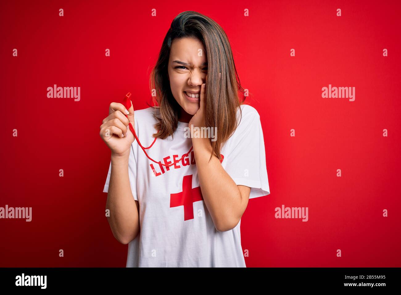 Young beautiful brunette lifeguard girl wearing t-shirt with red cross ...