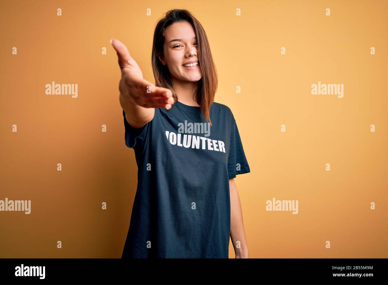 Young beautiful brunette girl doing volunteering wearing t-shirt with ...
