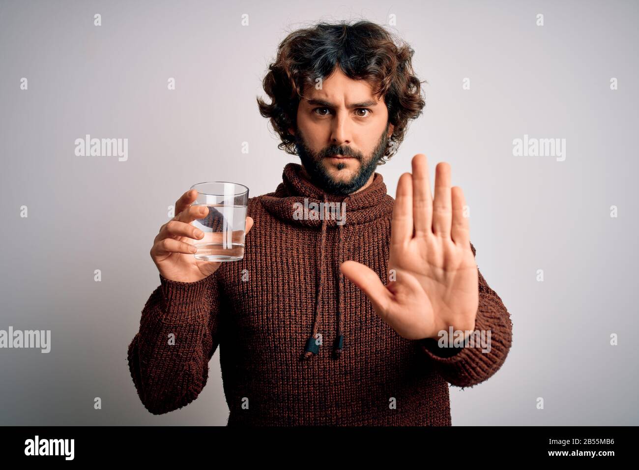 Young handsome man with beard drinking glass of water over isolated ...