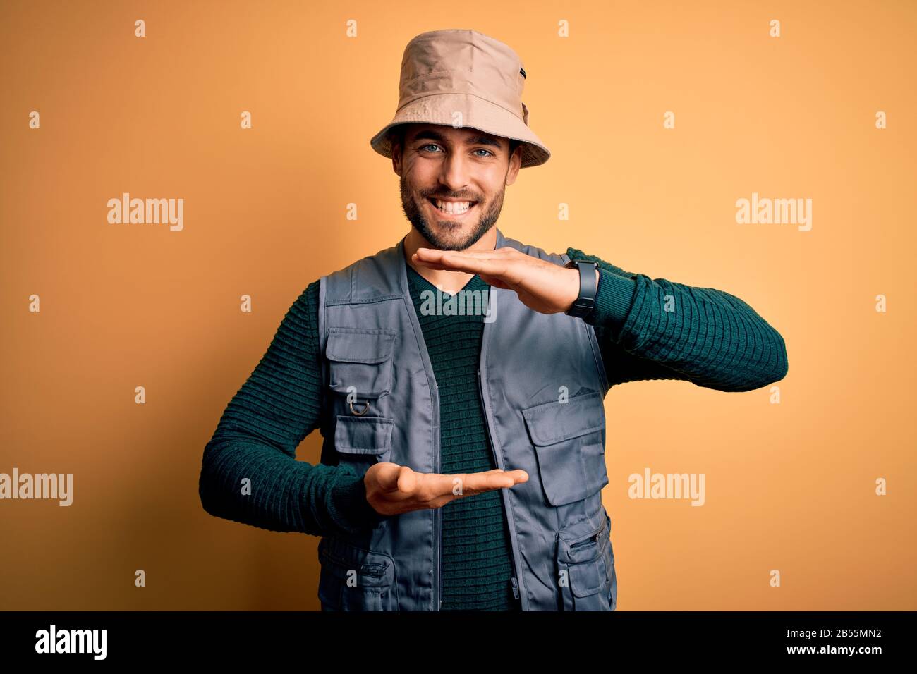 Handsome tourist man with beard on vacation wearing explorer hat over ...