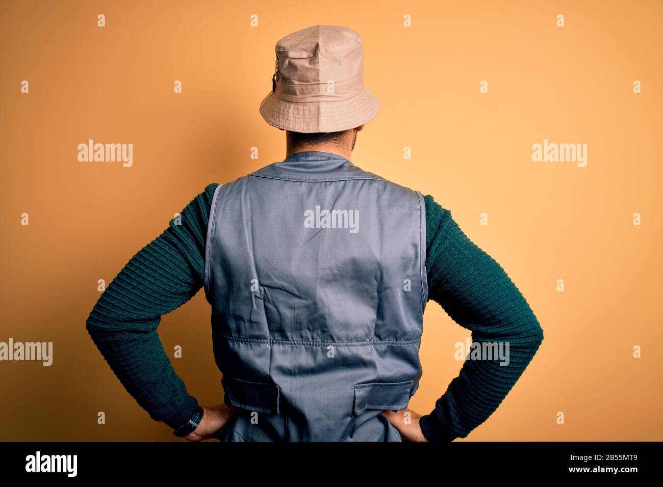 Handsome tourist man with beard on vacation wearing explorer hat over ...