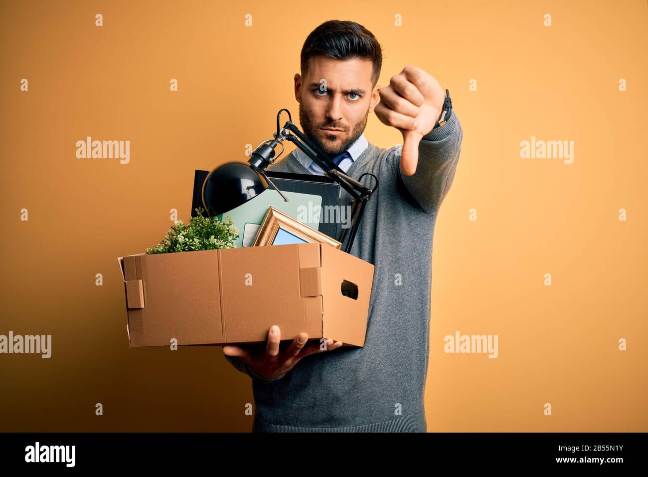 Young business man holding office box being fired from job over yellow ...