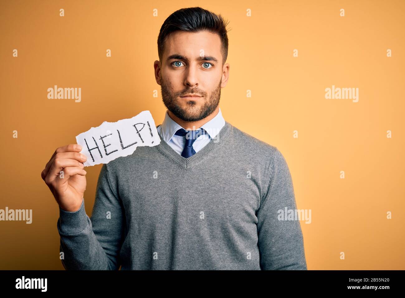 Young overworked business man asking for help holding paper over yellow ...