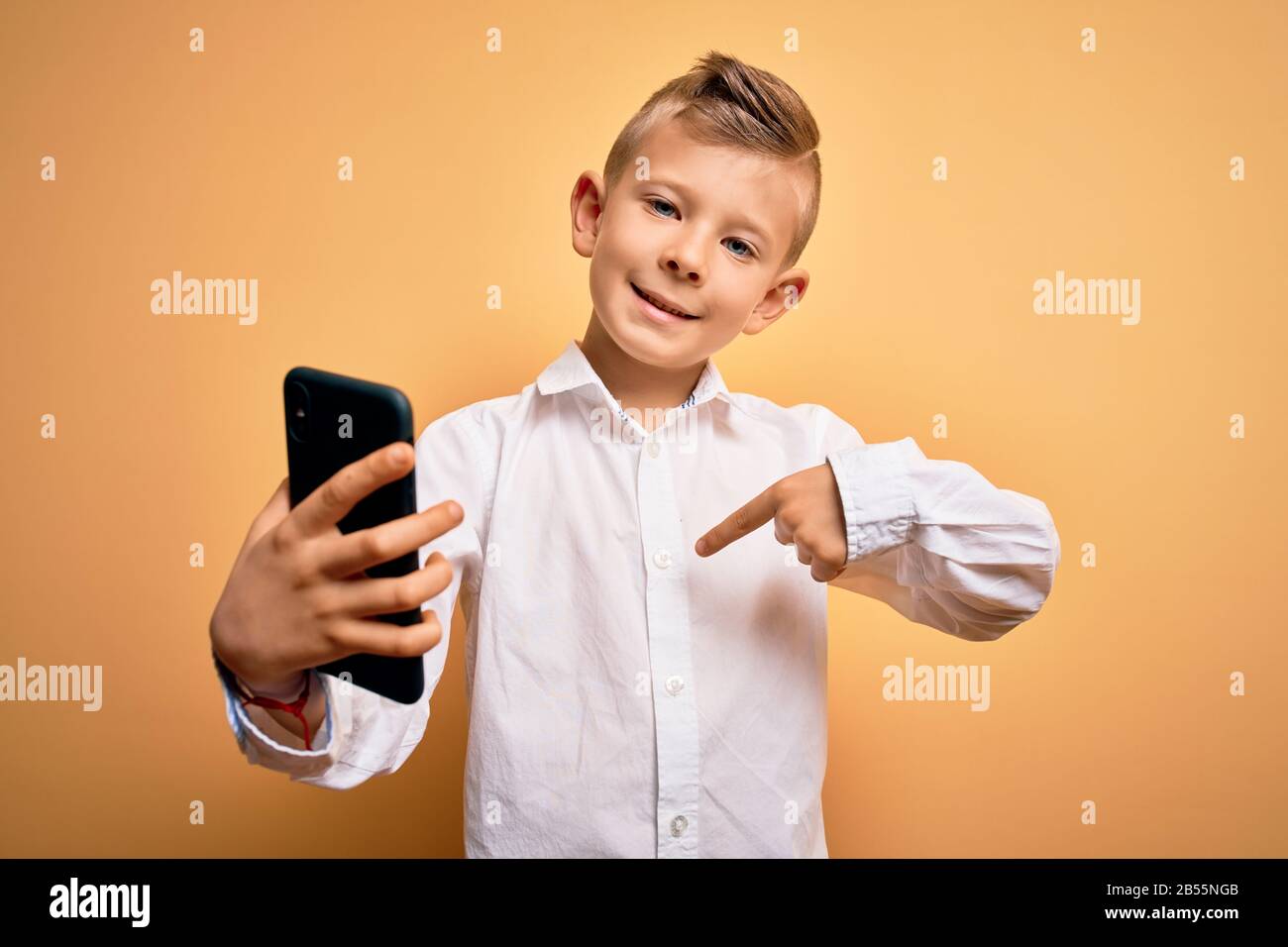 Young little caucasian kid using smartphone and looking at the screen ...