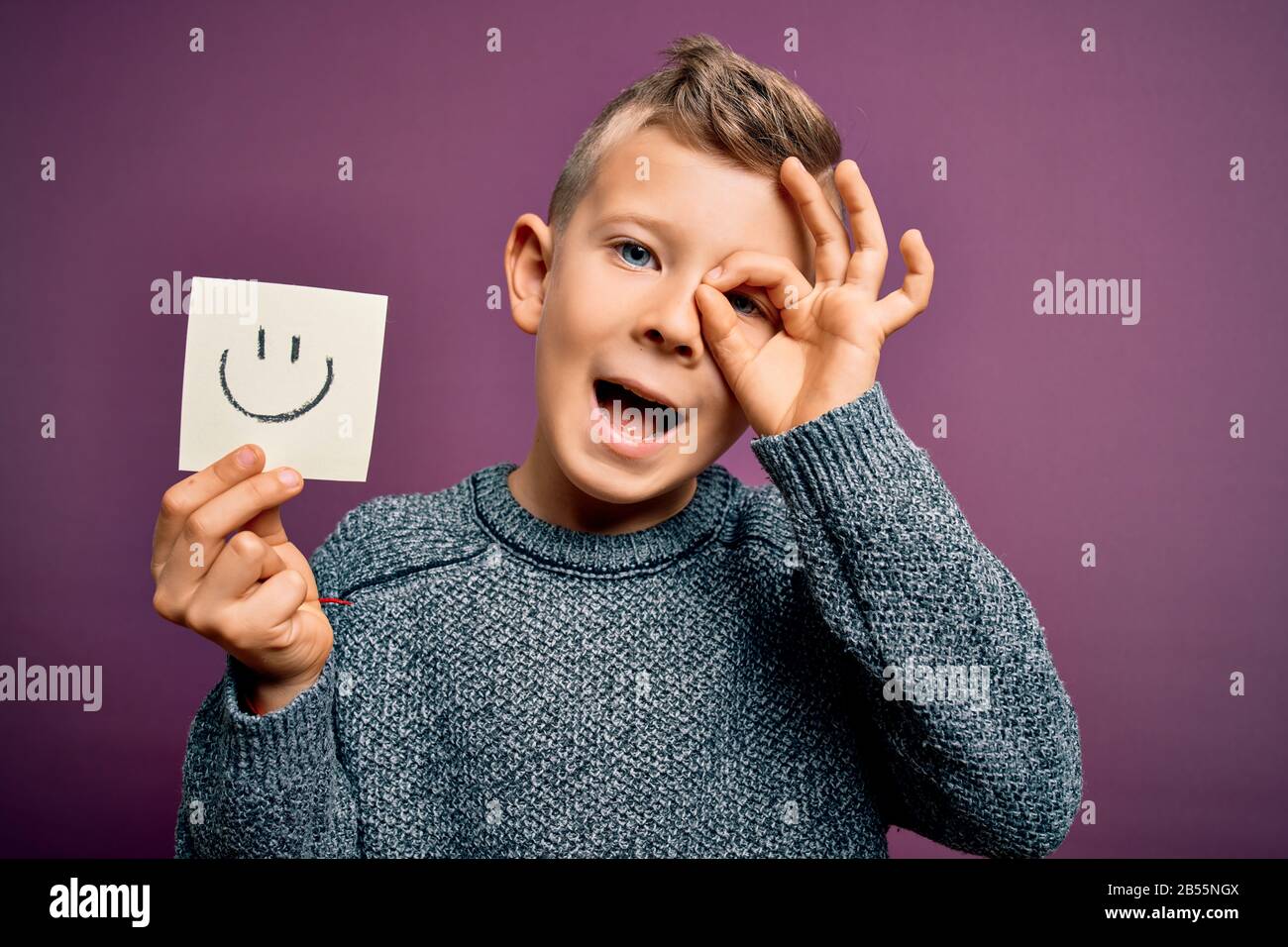 Young little caucasian kid showing smiley face on a paper note as happy ...