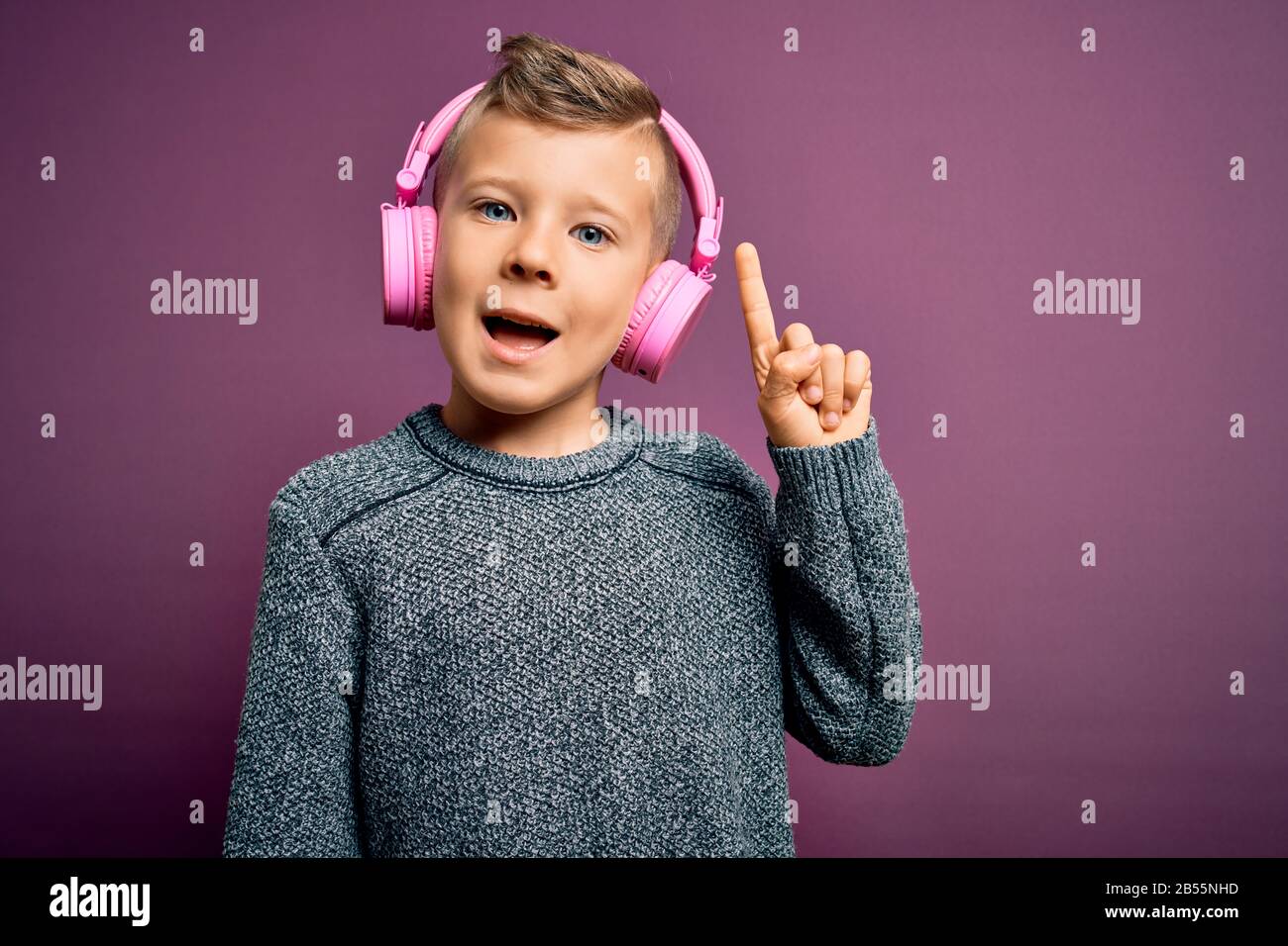 Young little caucasian kid wearing headphones listening to music over ...