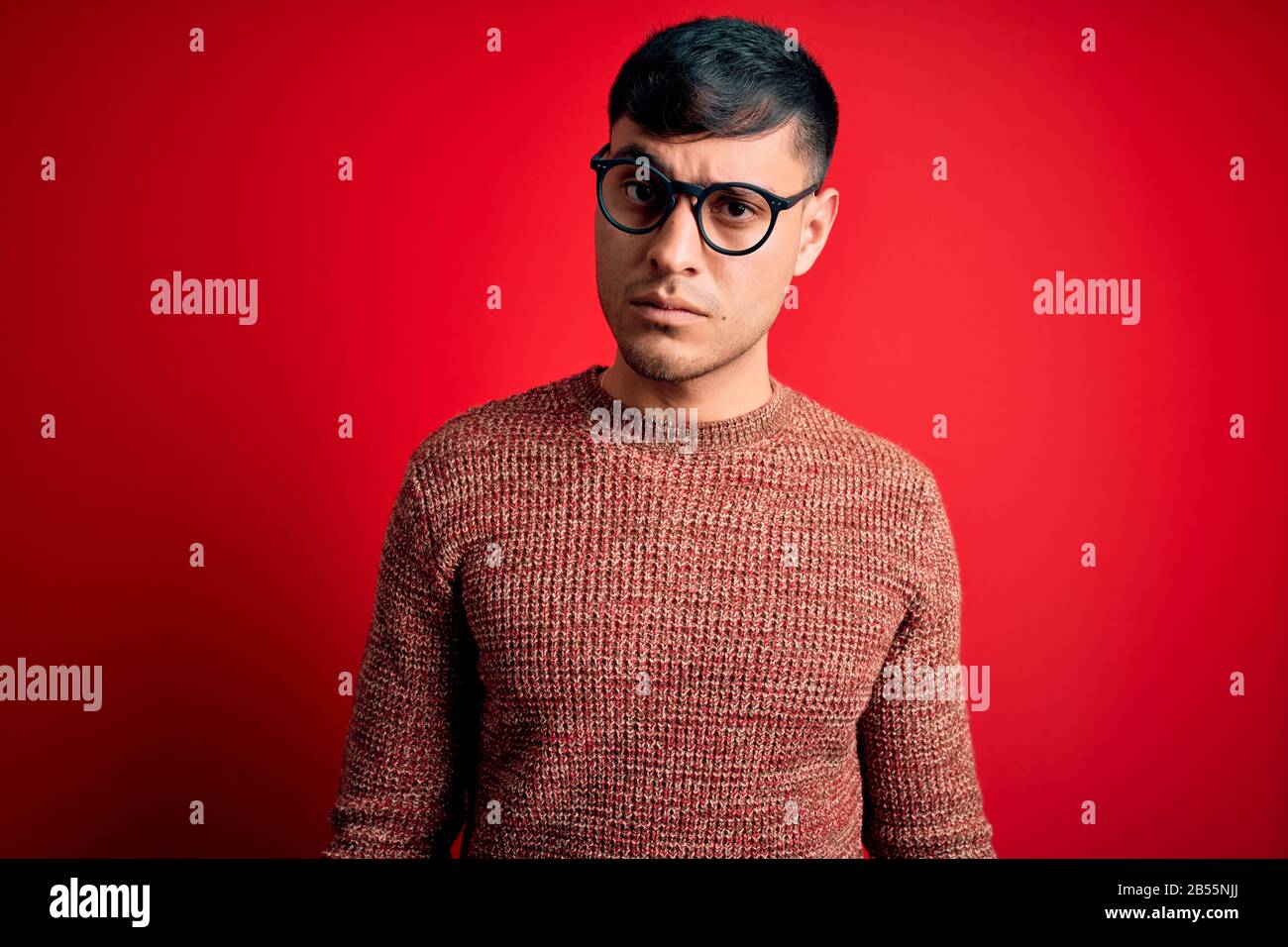 Young handsome hispanic man wearing nerd glasses over red background ...