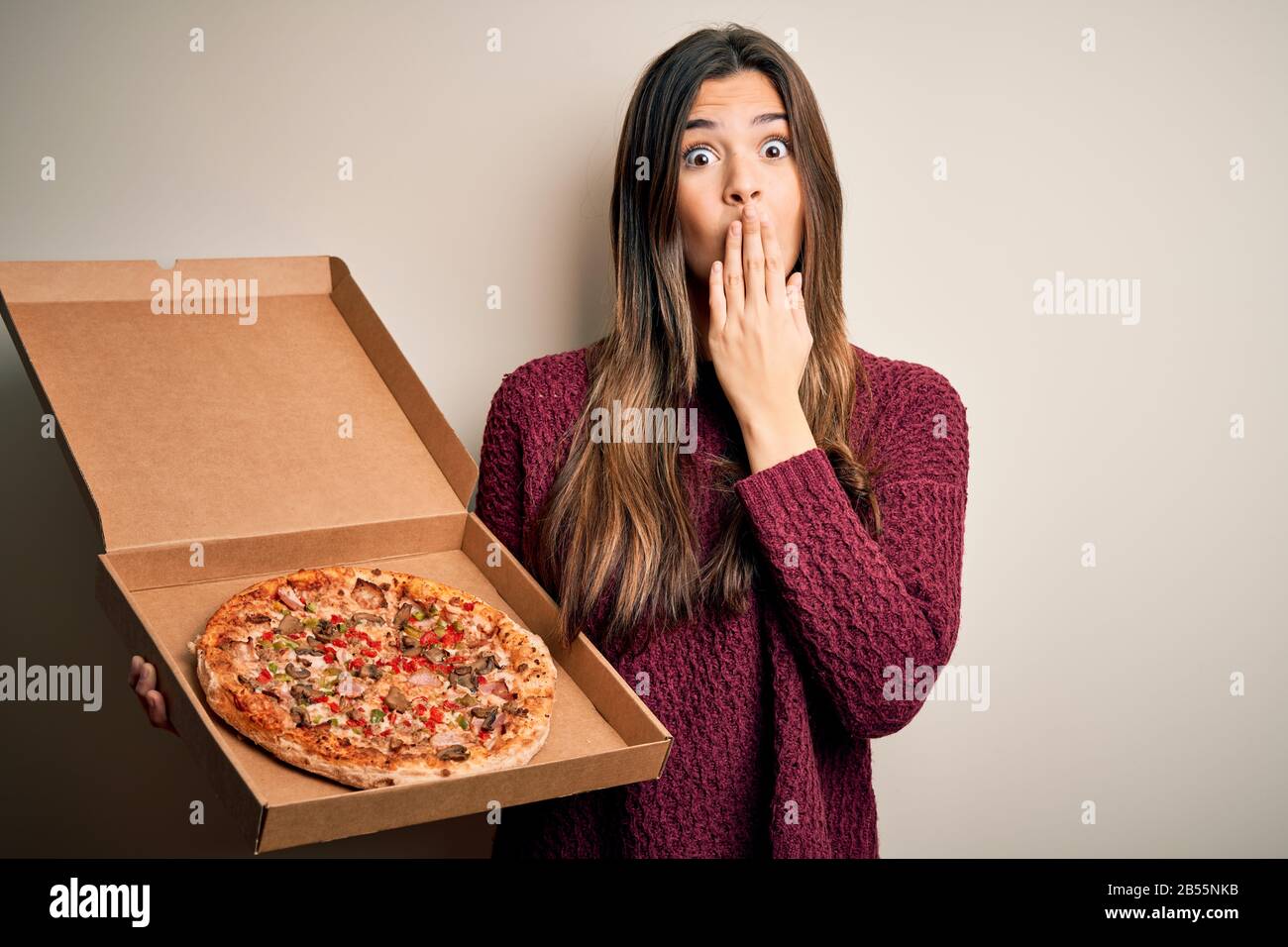 Young beautiful girl holding delivery box with Italian pizza standing ...