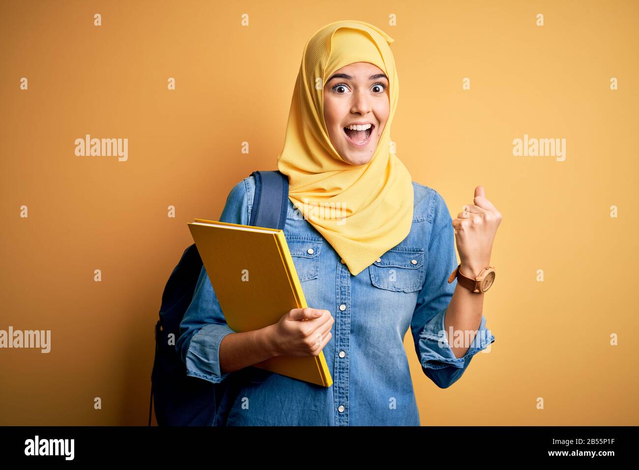 Young student girl wearing muslim hijab and backpack holding book over ...