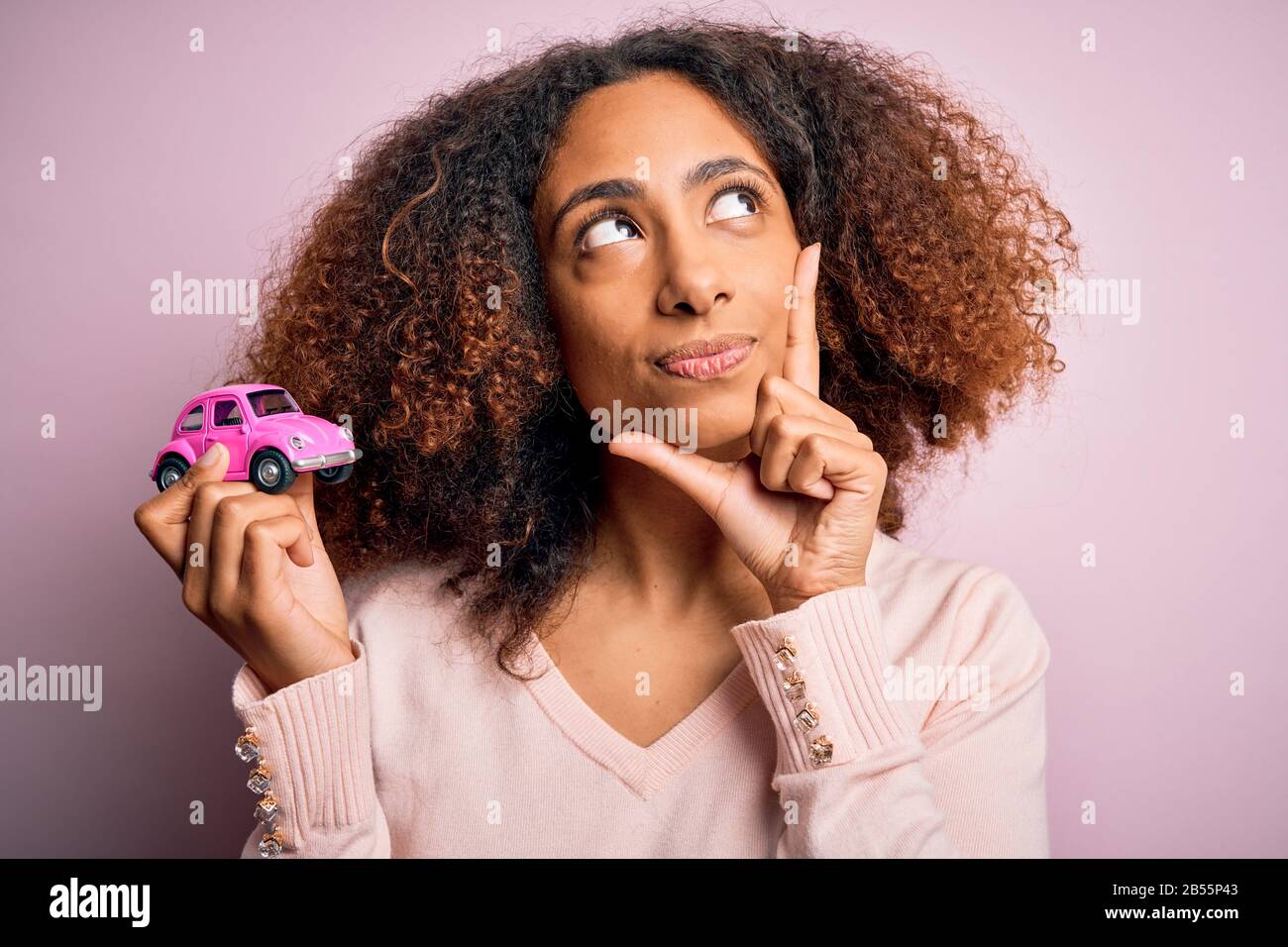 Young african american woman with afro hair holding with hand small ...