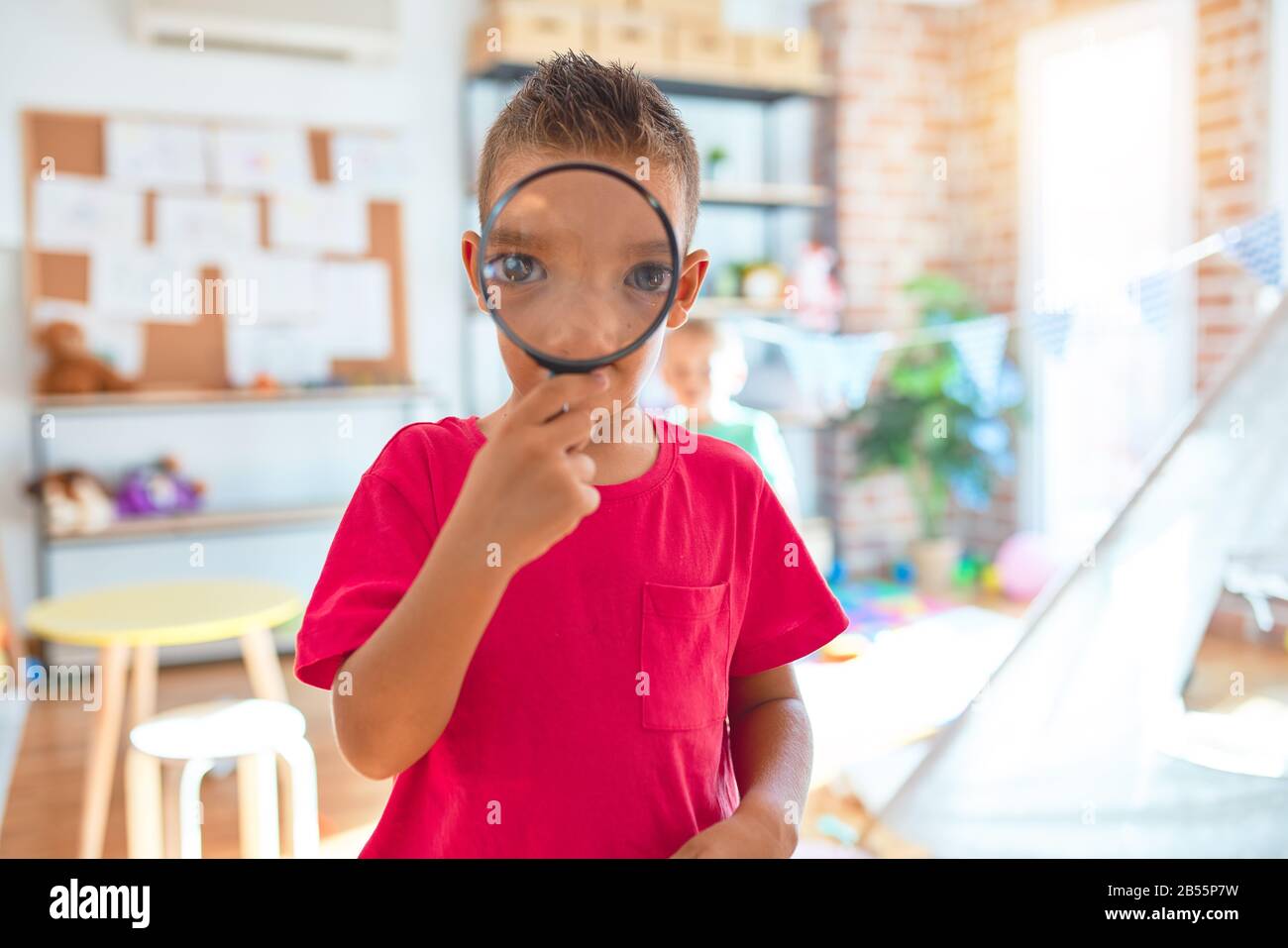 Adorable toddler playing using loupe around lots of toys at ...