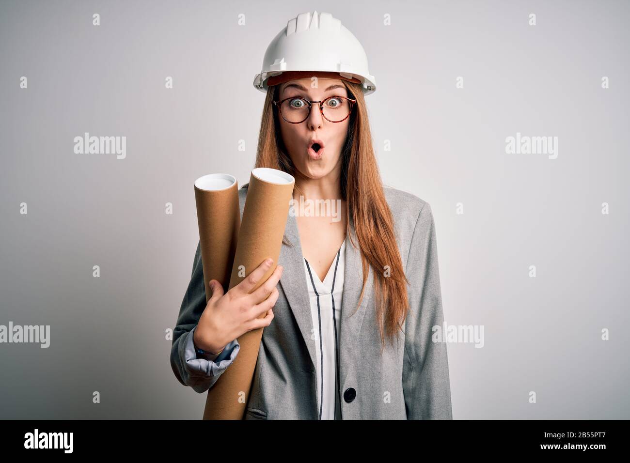 Young beautiful redhead architect woman wearing glasses and safety ... Young beautiful redhead architect woman wearing glasses and safety ...