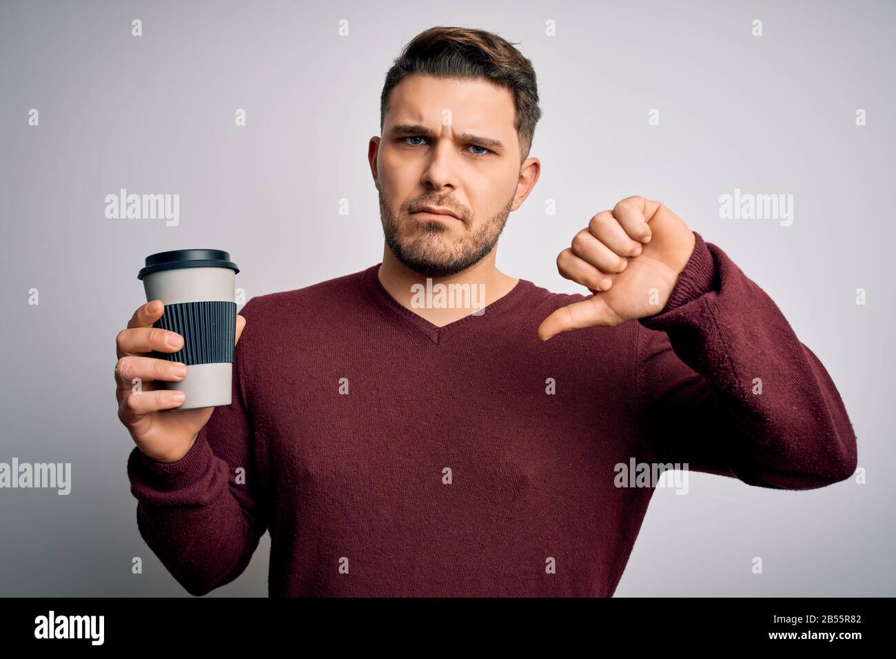 Young man with blue eyes drinking coffee from take away plastic bottle ...