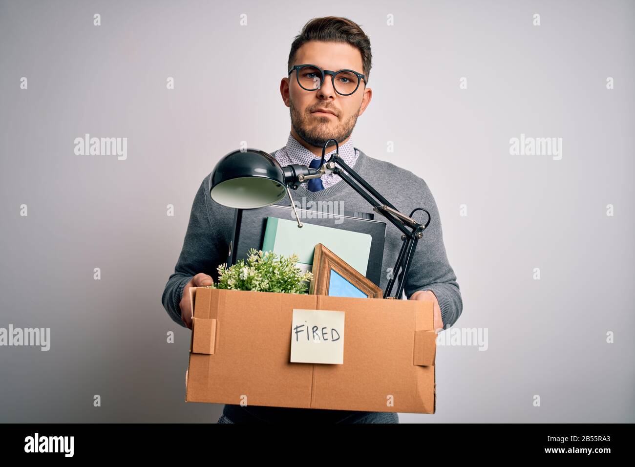 Young business man with blue eyes holding box from the office beeing ...