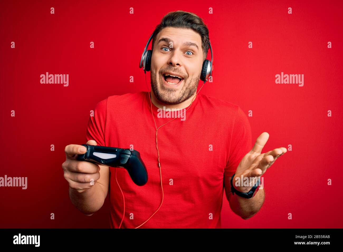 Young gamer man with blue eyes playing video games using gamepad ...