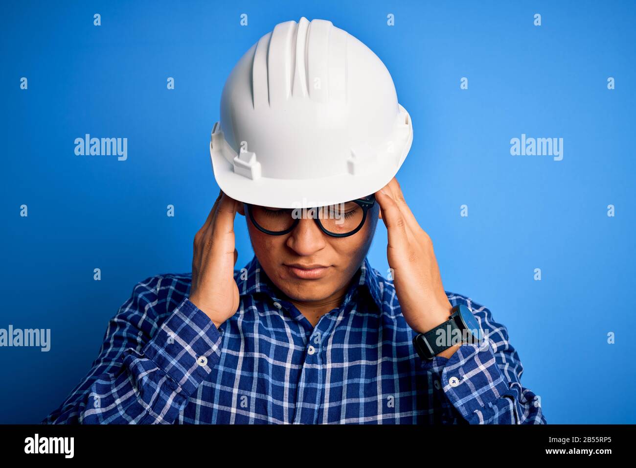 Young handsome engineer latin man wearing safety helmet over isolated ...