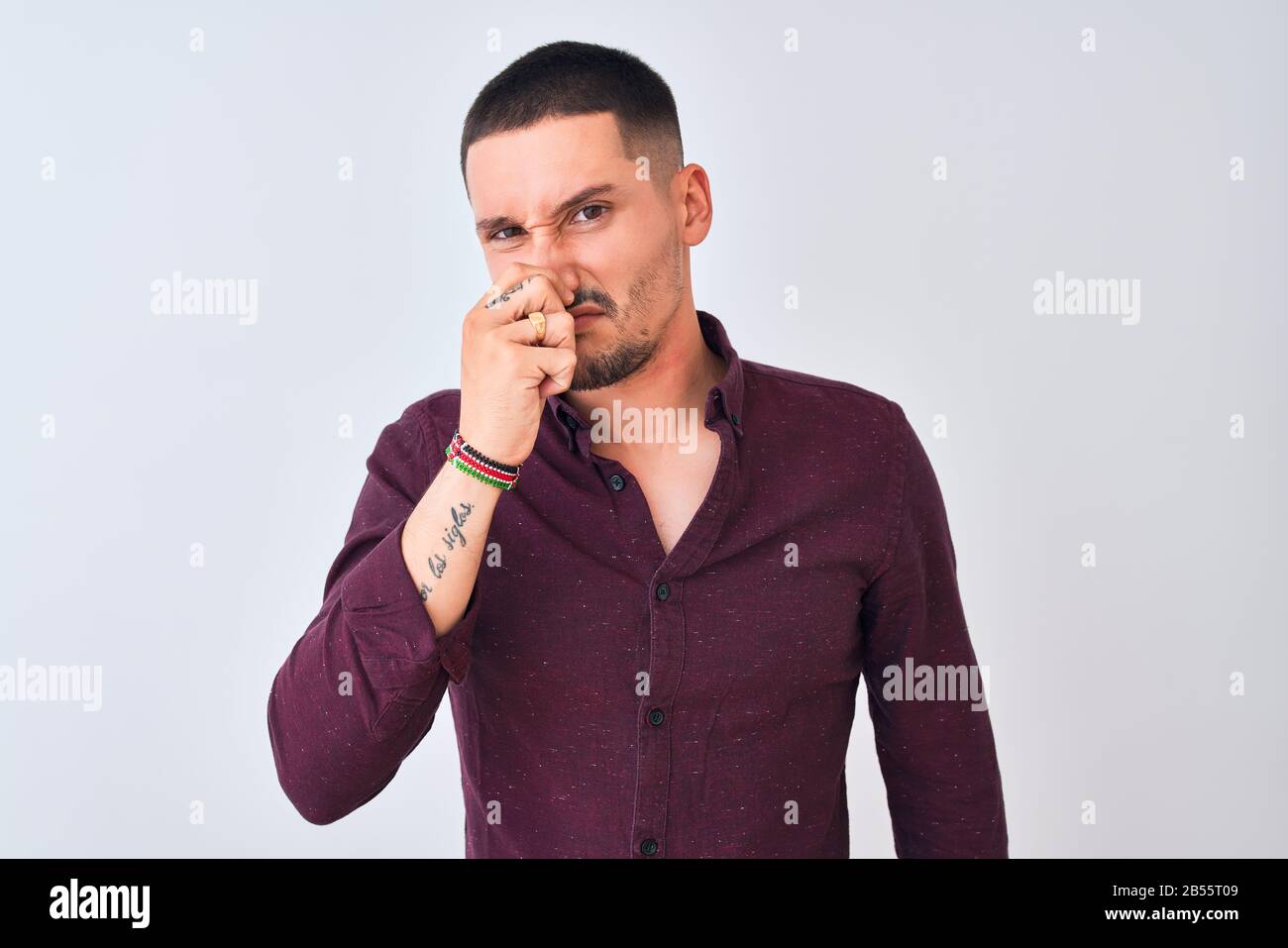 Young handsome business man standing over isolated background smelling ...