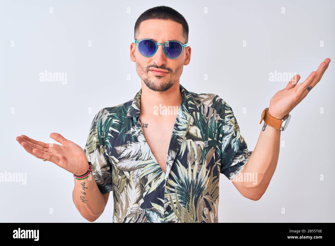 Young handsome man wearing Hawaiian sumer shirt and blue sunglasses ...