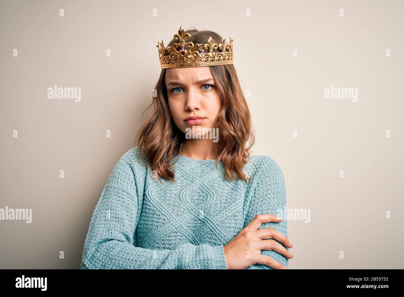 Young blonde girl wearing queen golden crown over isolated background ...