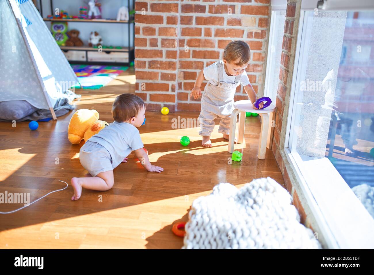 Beautiful toddlers playing around lots of toys at kindergarten Stock ...
