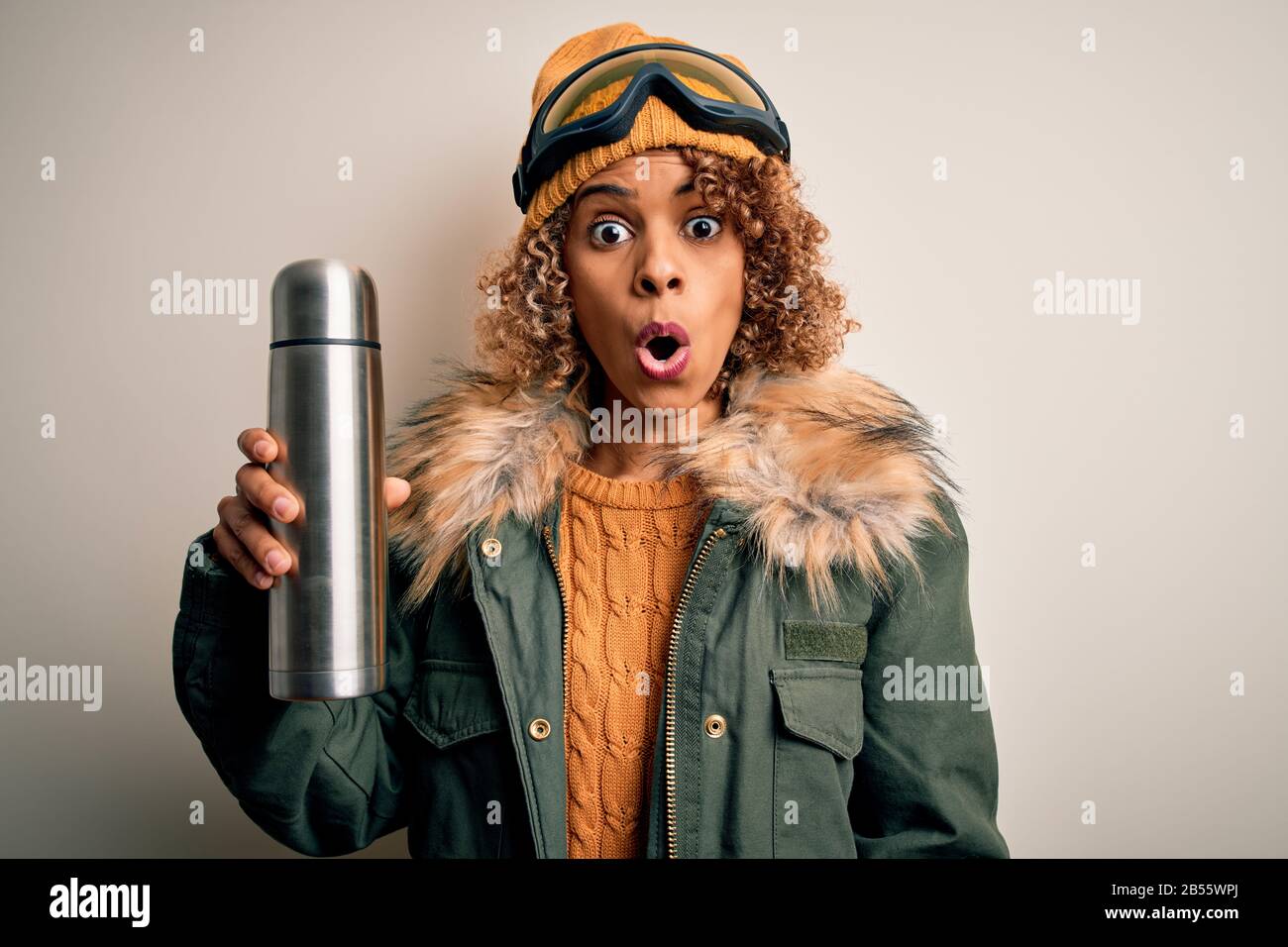 Young african american skier woman wearing ski goggles drinking thermo ...