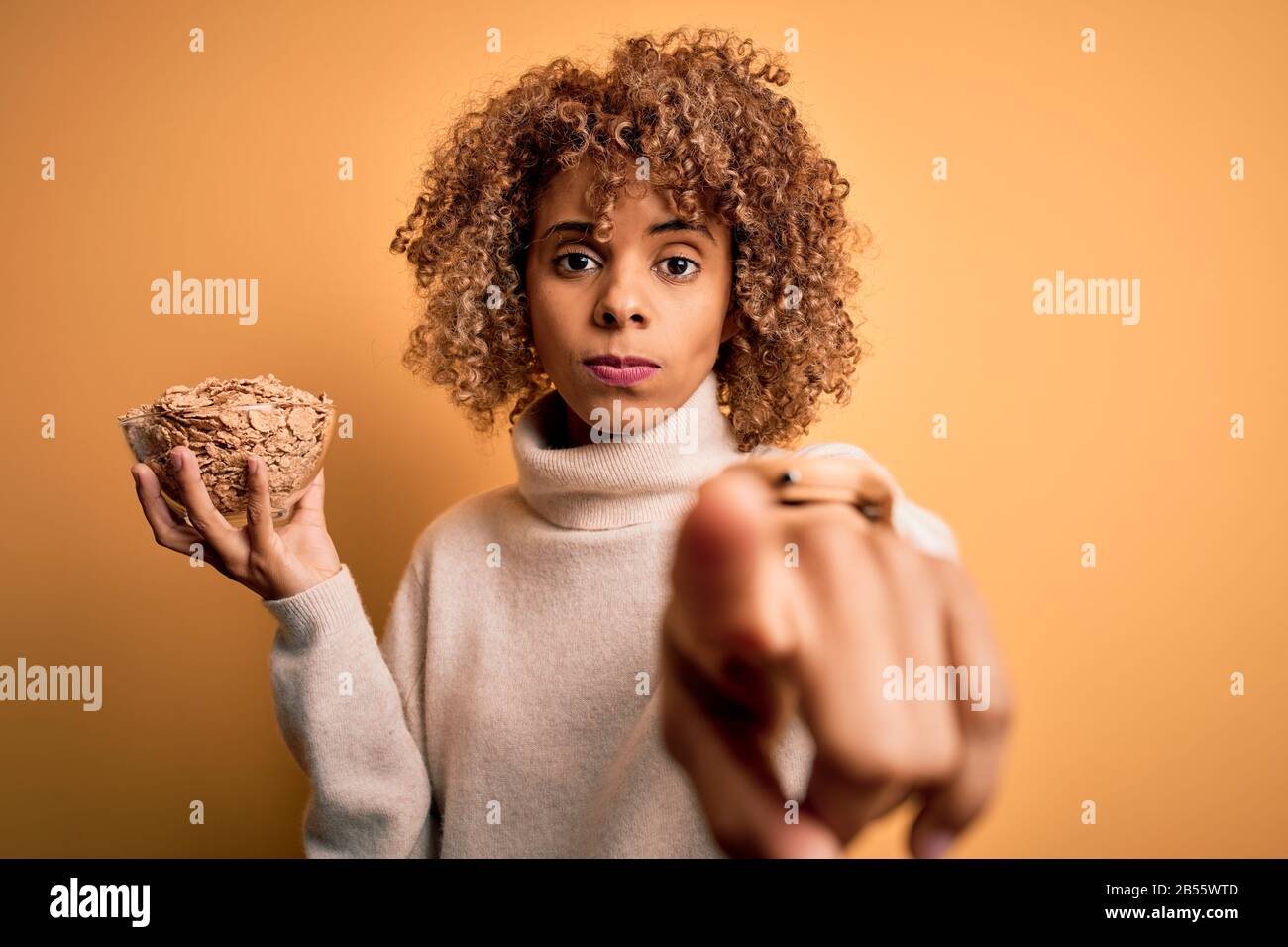 Young african american curly woman holding bowl with healthy cornflakes ...
