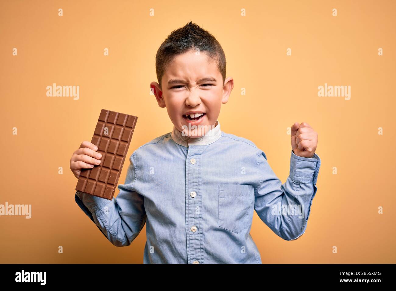 Young little boy kid eating sweet chocolate bar for dessert over ...