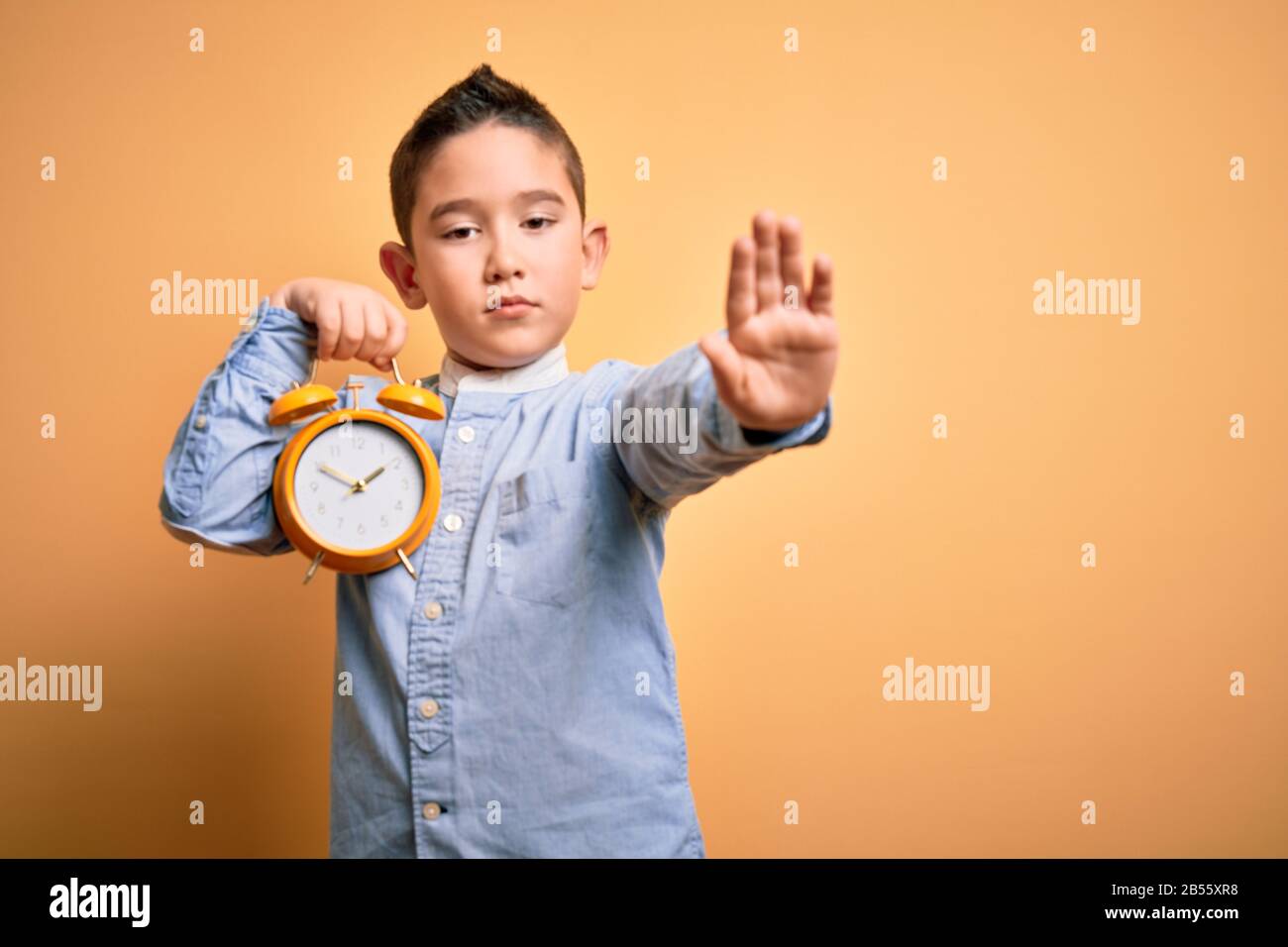 Young little boy kid holding classic bell alarm clock over isolated ...