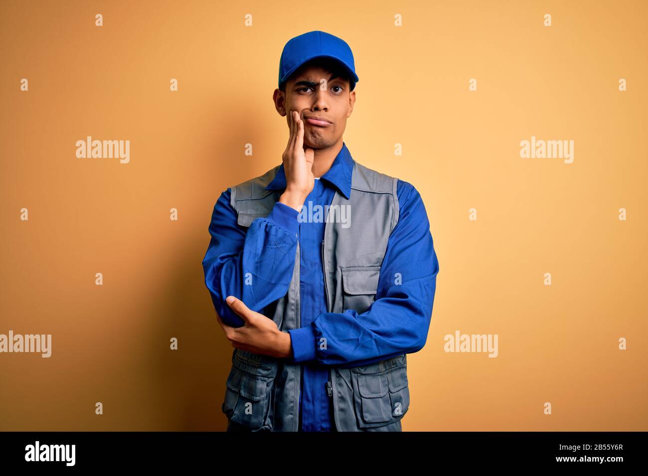 Young handsome african american handyman wearing worker uniform and cap ...