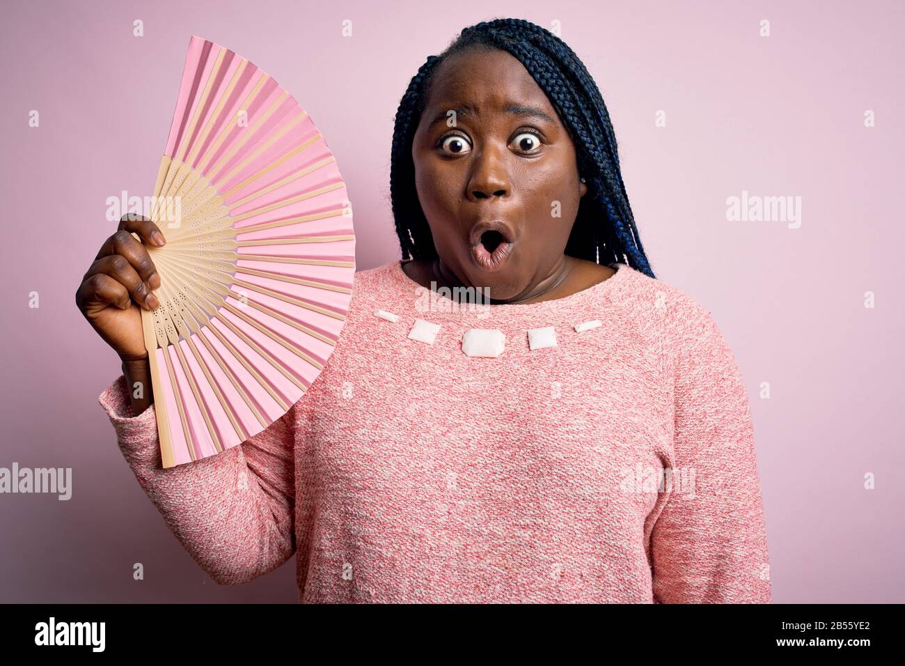 Young african american plus size woman with braids using hand fan over ...