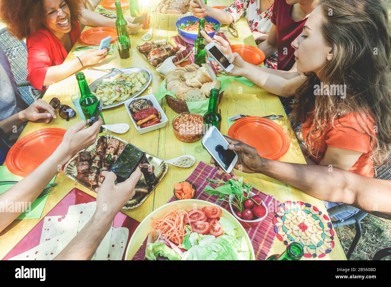 Group of young cheerful students using mobile phones at barbecue ...