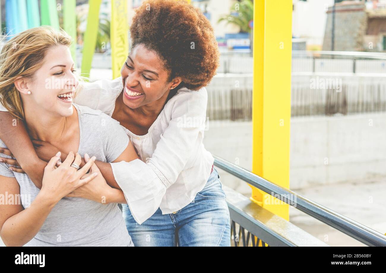 Happy women friends laughing and walking on colorful bridge - Young ...