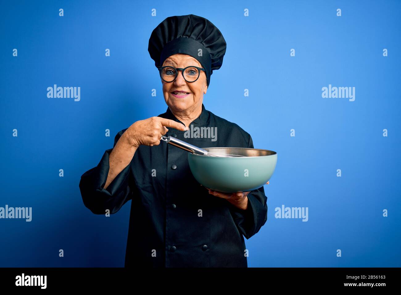 Senior beautiful grey-haired chef woman wearing cooker uniform and hat ...
