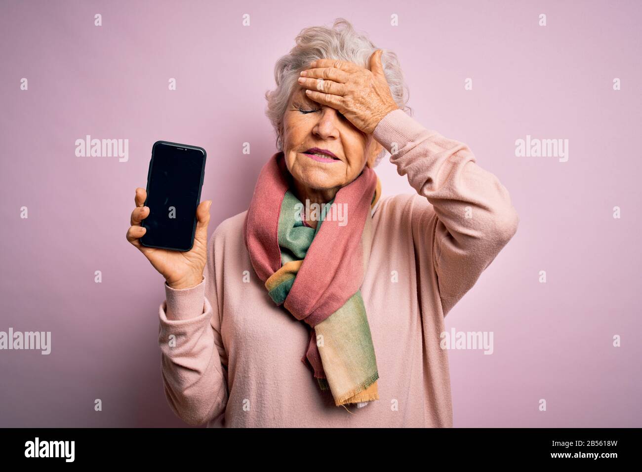 Senior beautiful grey-haired woman holding smartphone showing screen ...